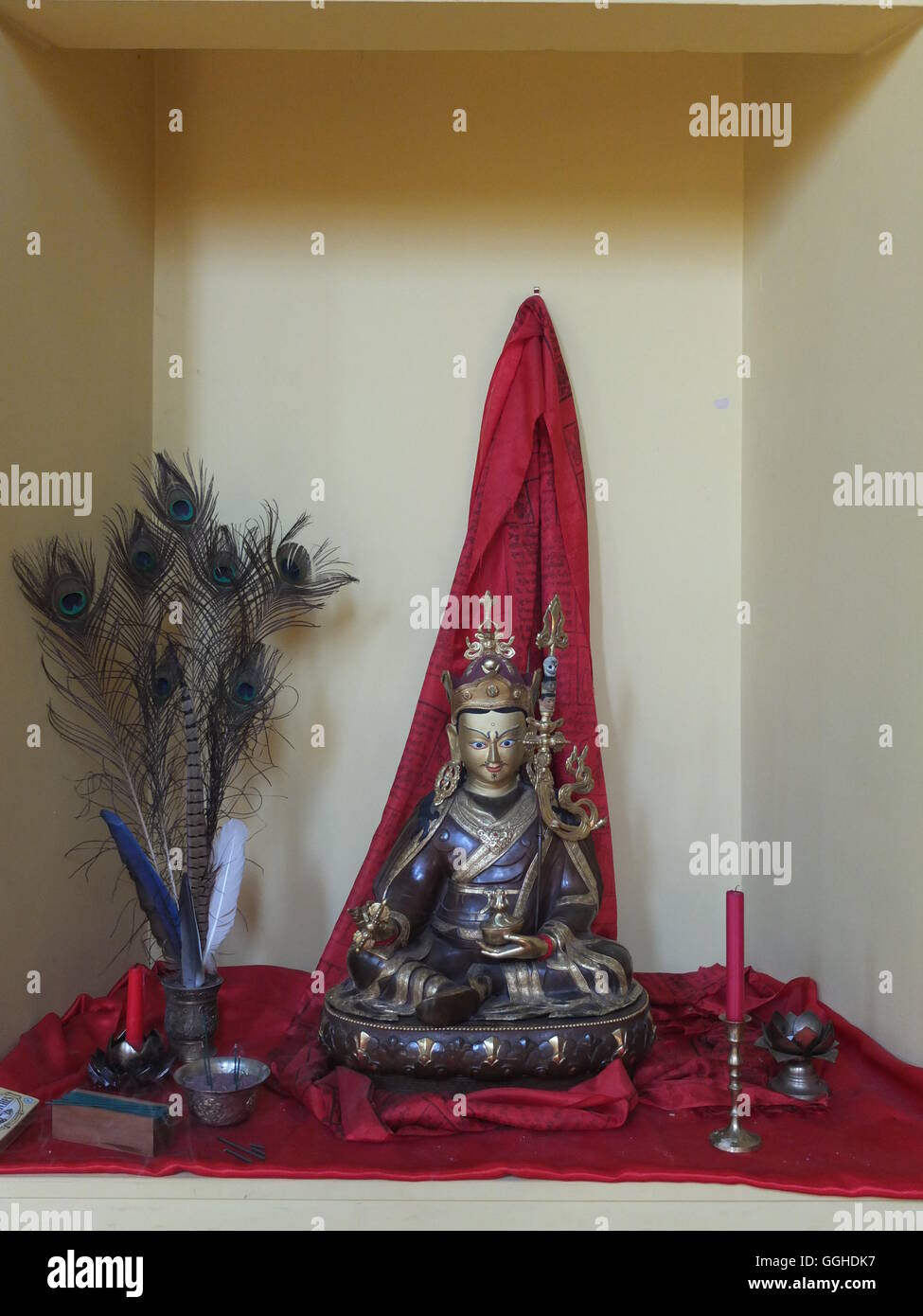 A shrine with statue, peacock feathers, incense and candles at Sheffield Buddhist Centre ...
