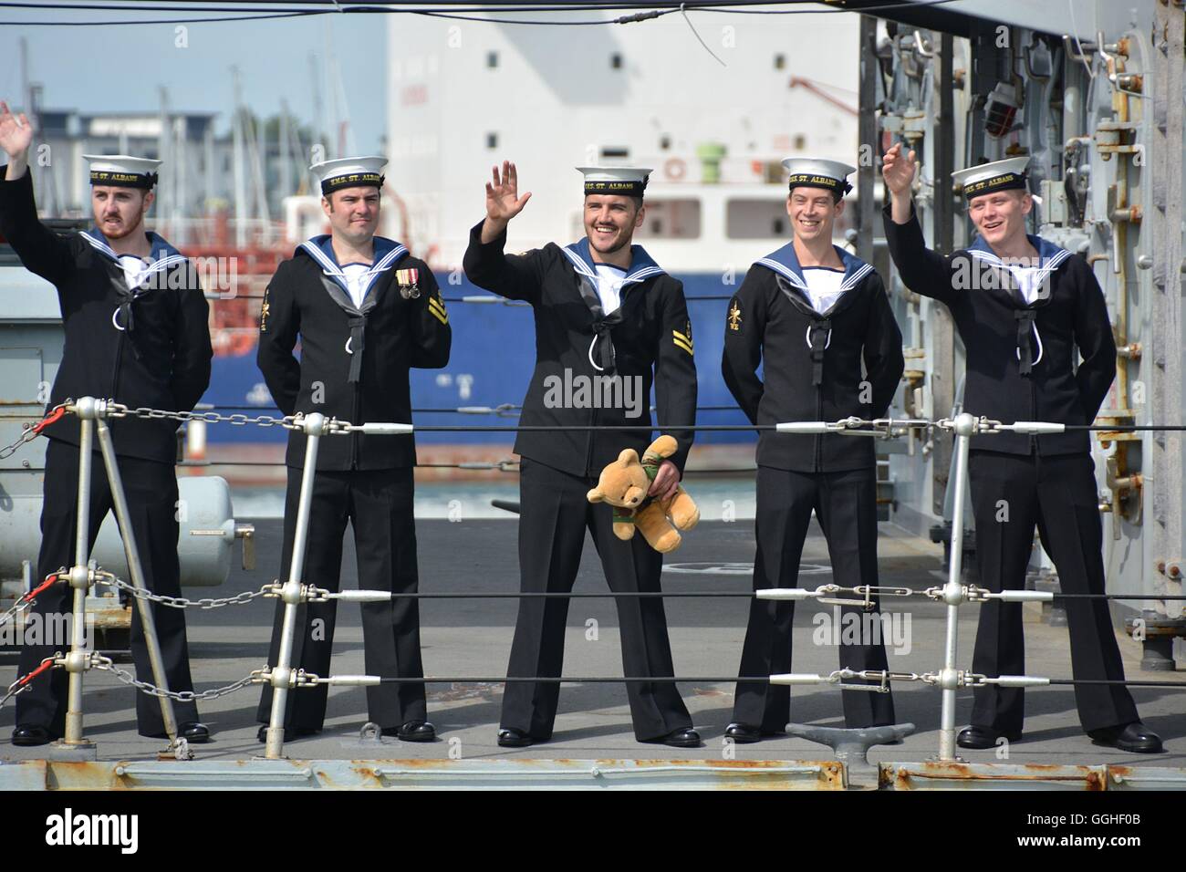 A sailor grips a teddy bear for his loved ones as he returns aboard HMS ...