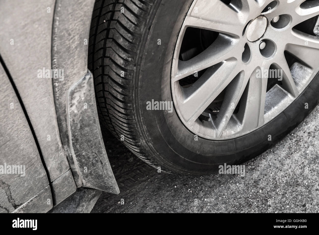 Dirty unidentifiable car wheel with light alloy disc on country road ...