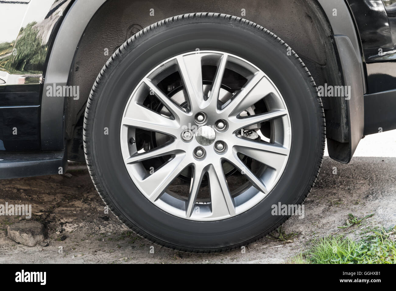 Modern unidentifiable suv car wheel on rural road, closeup frontal ...