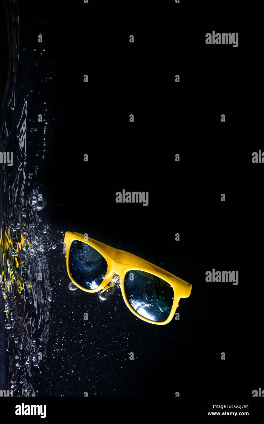 Yellow sunglasses splashing into water on black background. eyewear ...