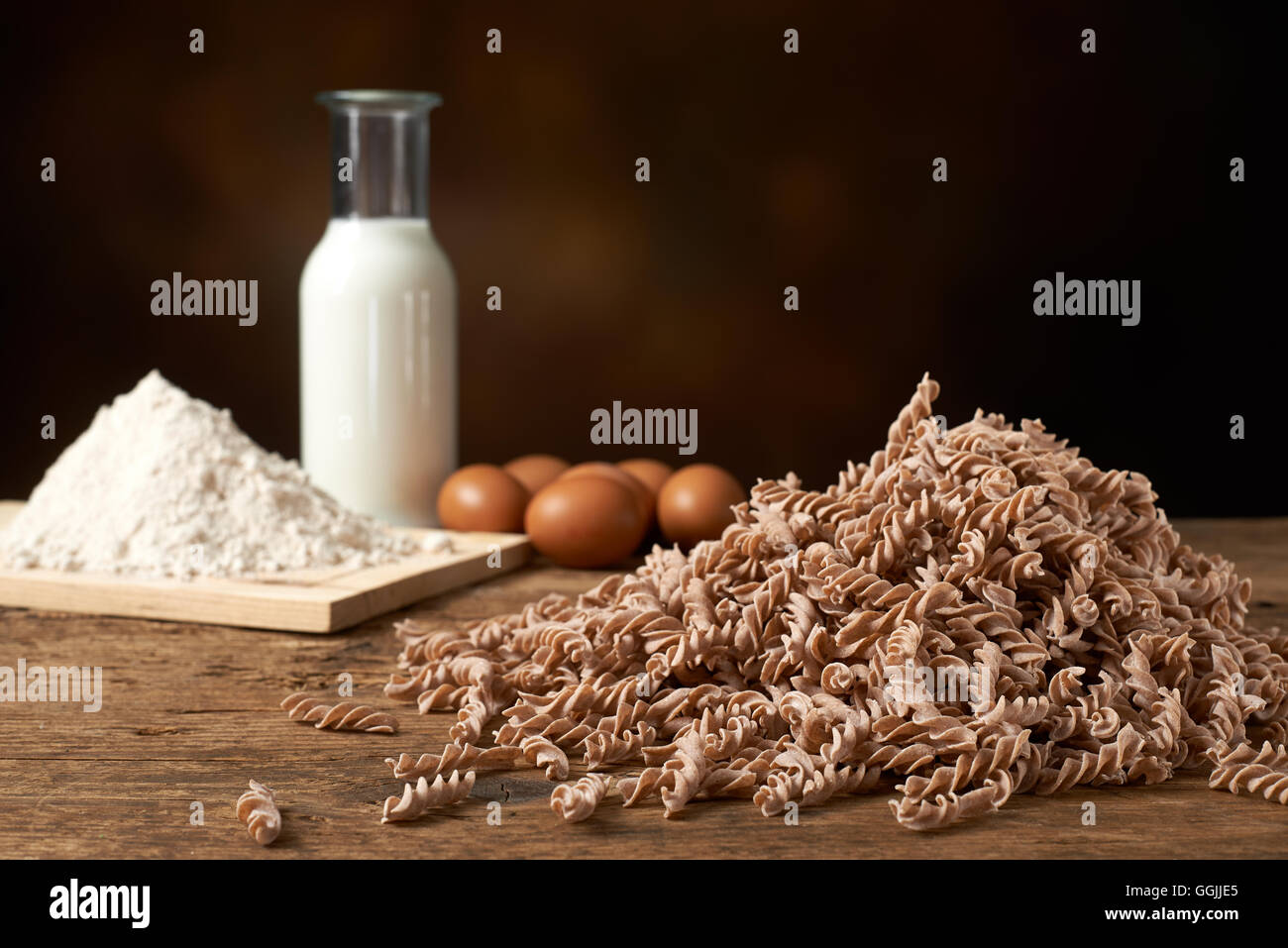 uncooked spiral pasta with manufacturing materials , flour eggs and ...