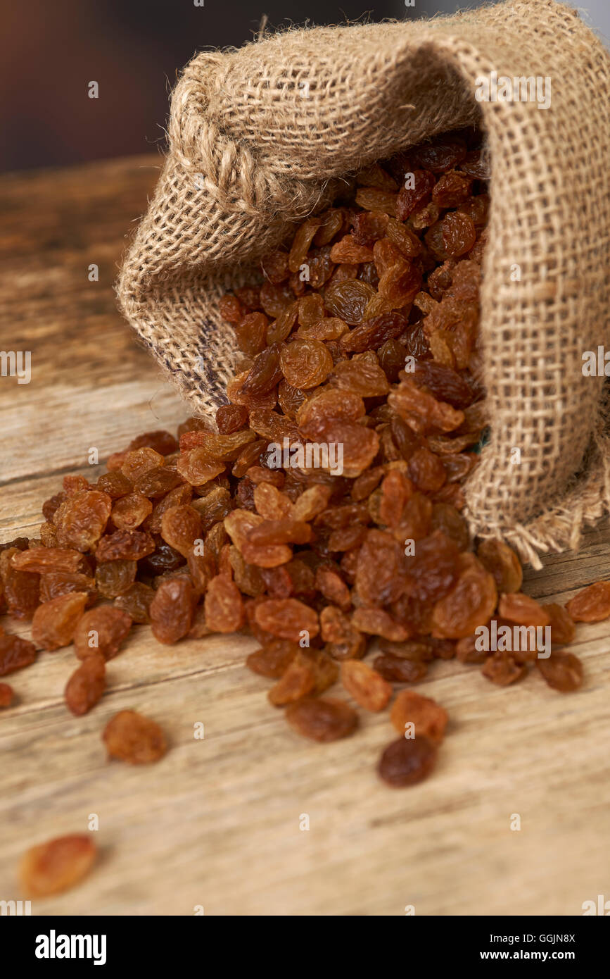 Golden raisins in burlap bag over wooden table Stock Photo - Alamy