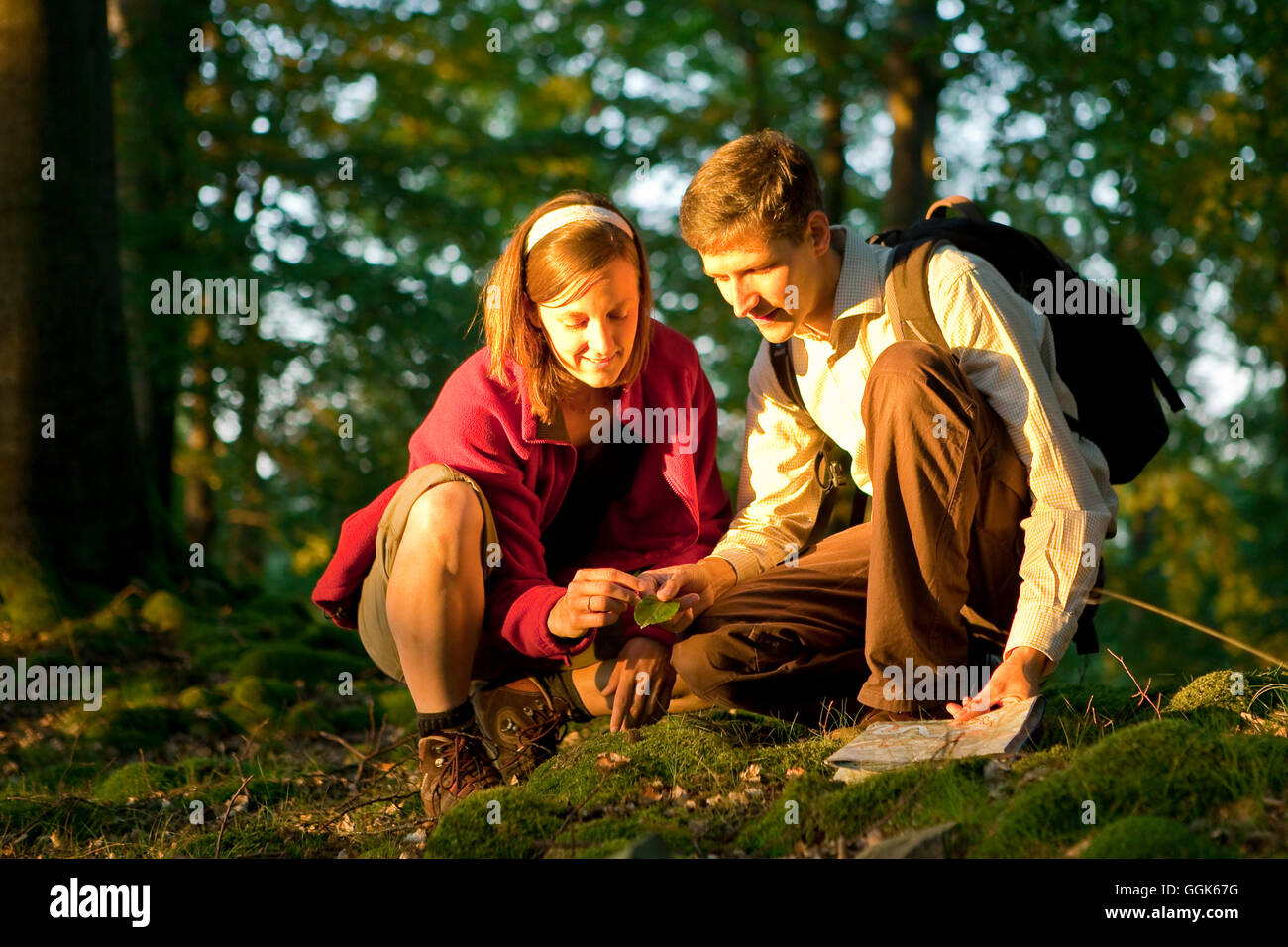 A couple admiring the leaf of a beech tree in the Hagenstein forest in ...