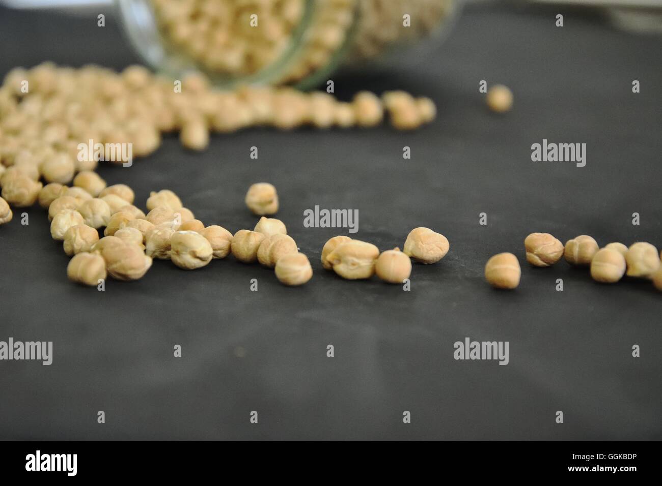 Inverted glass jar of chickpeas on black background with space for text ...
