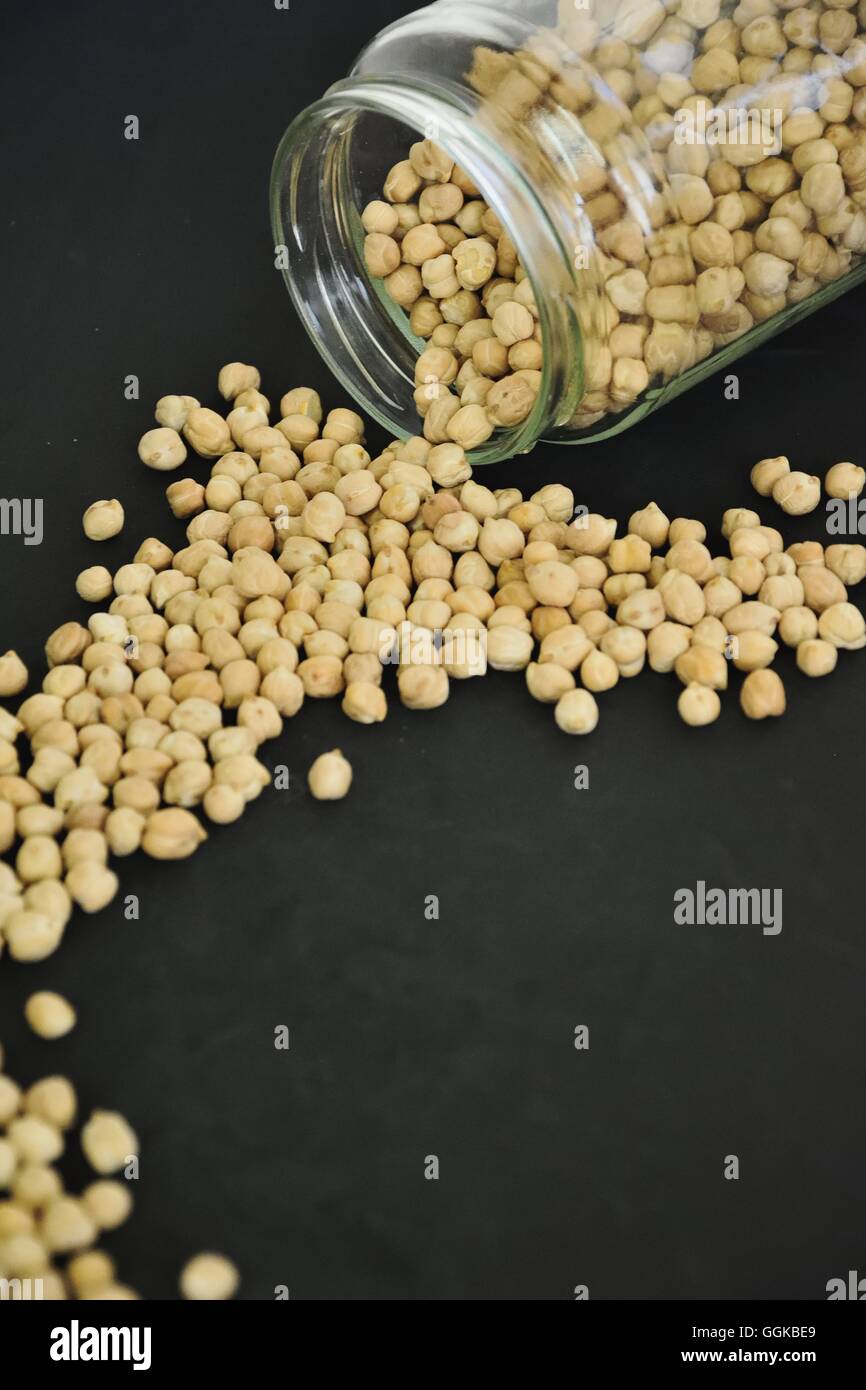 Inverted glass jar of chickpeas on black background with space for text ...