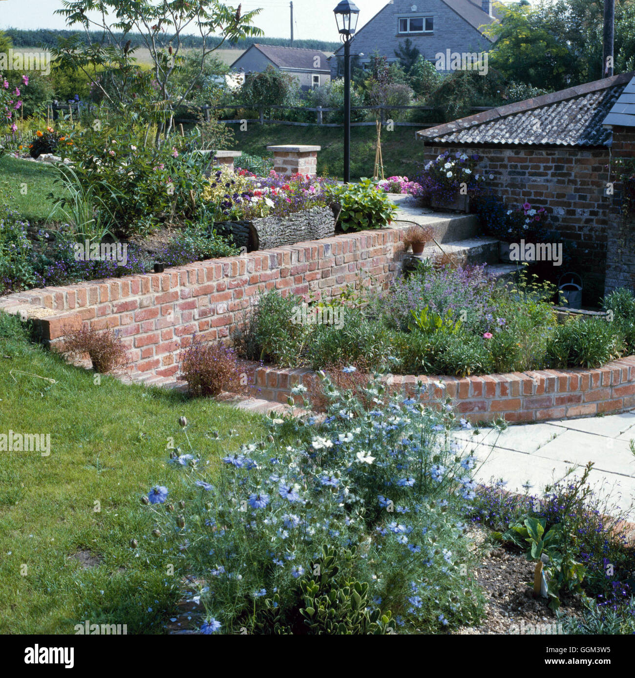 Patio- on sloping site with terraced beds PHS052498 Stock Photo - Alamy