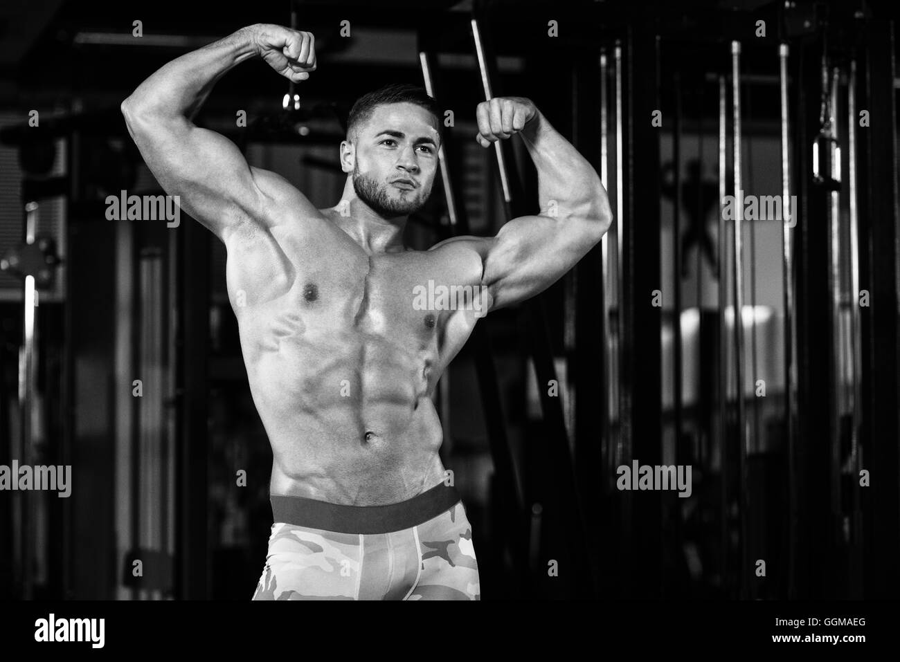 Young Man Standing Strong In The Gym And Flexing Muscles - Muscular ...