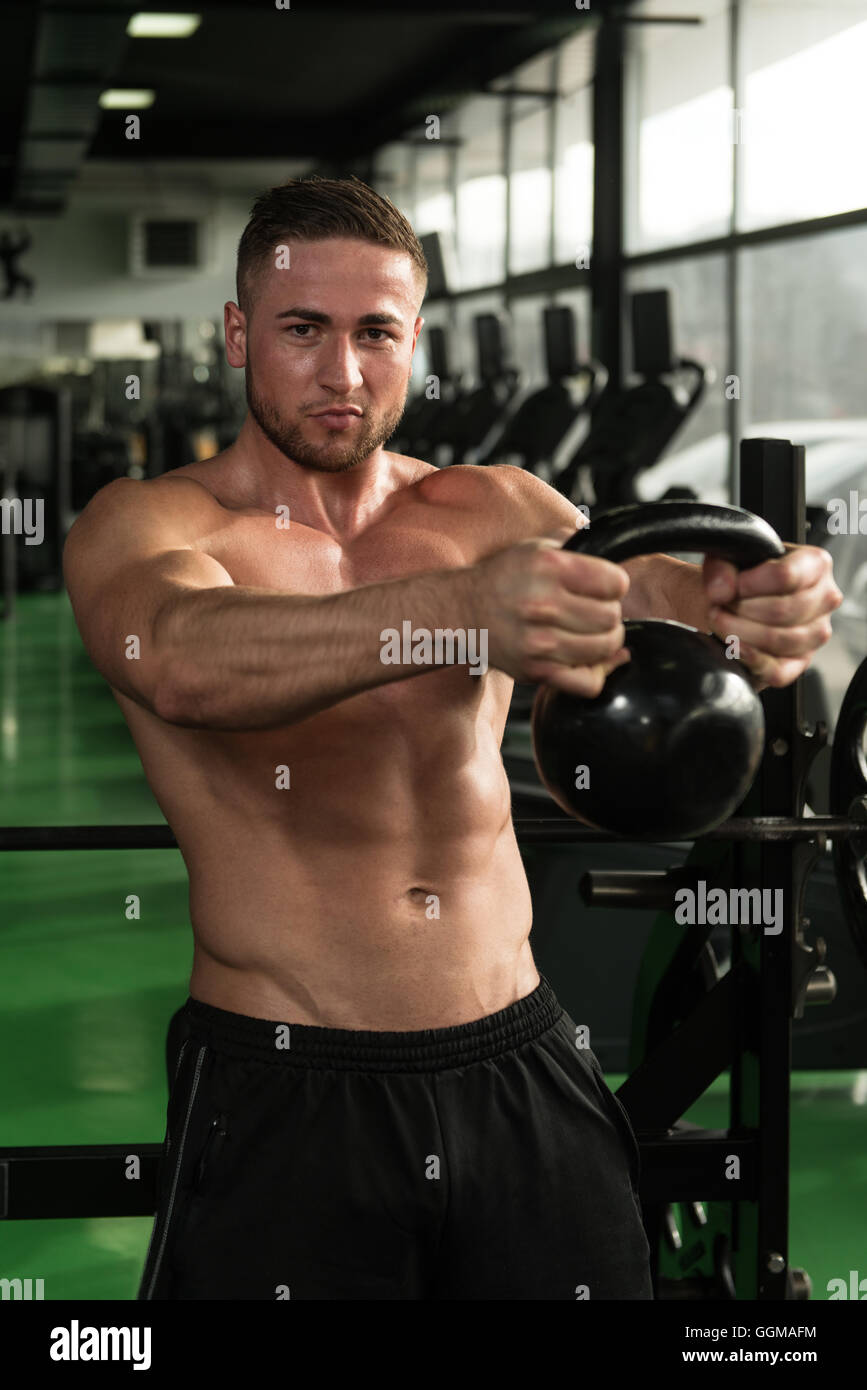 Young Man Exercising With Kettle Bell And Flexing Muscles - Muscular ...