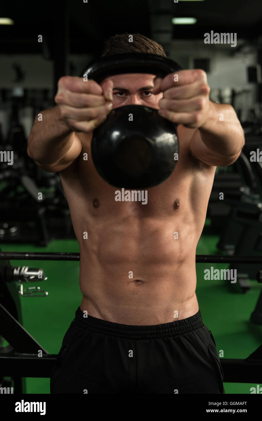 Young Man Exercising With Kettle Bell And Flexing Muscles - Muscular ...