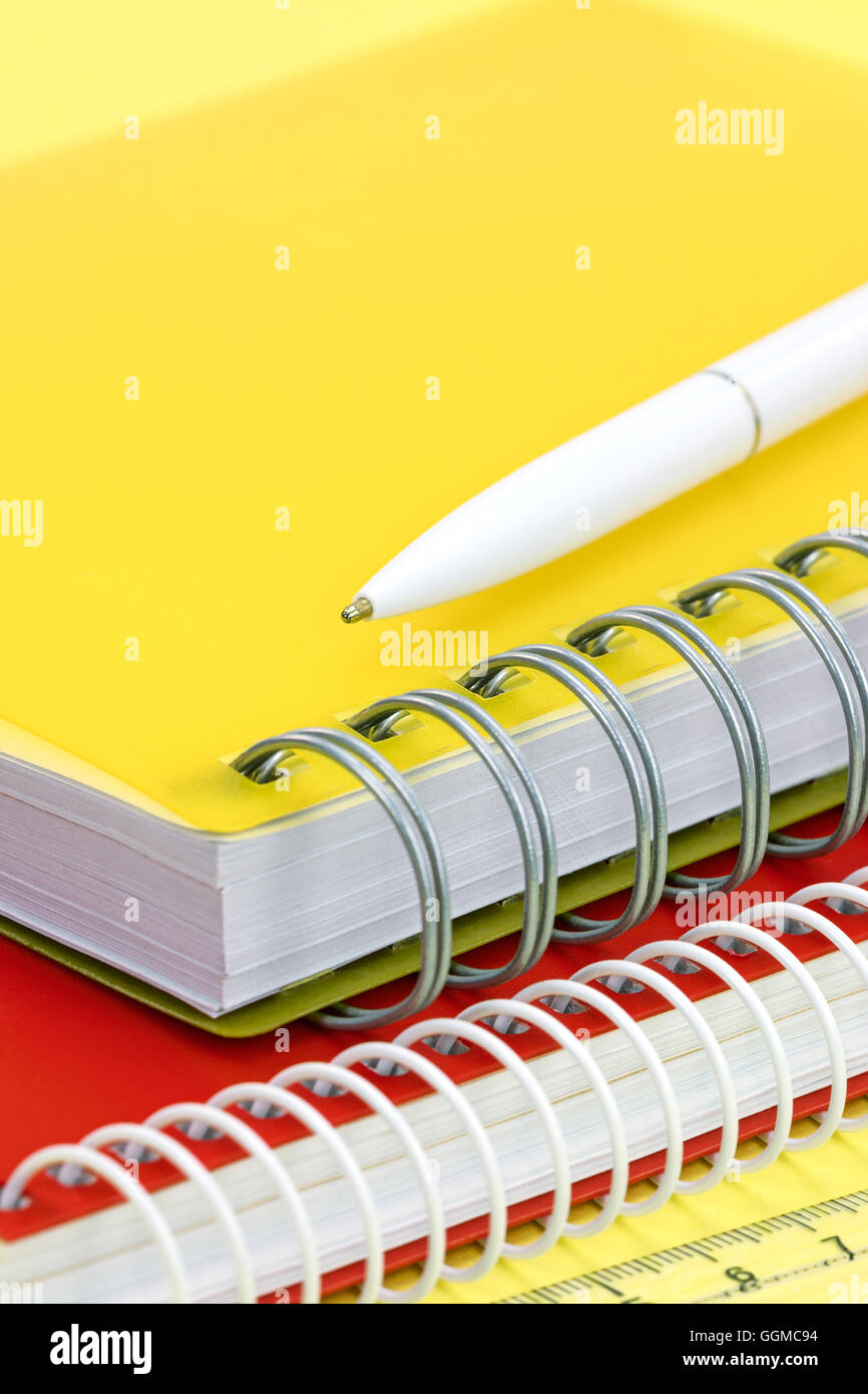 red, yellow notebooks pen and ruler on yellow board background, closeup ...