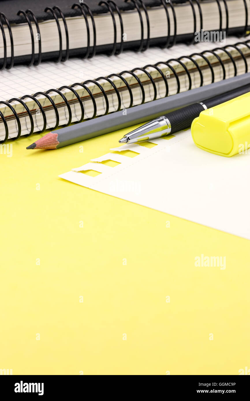 office supplies, pencils, marker notebooks lying on yellow writing desk ...