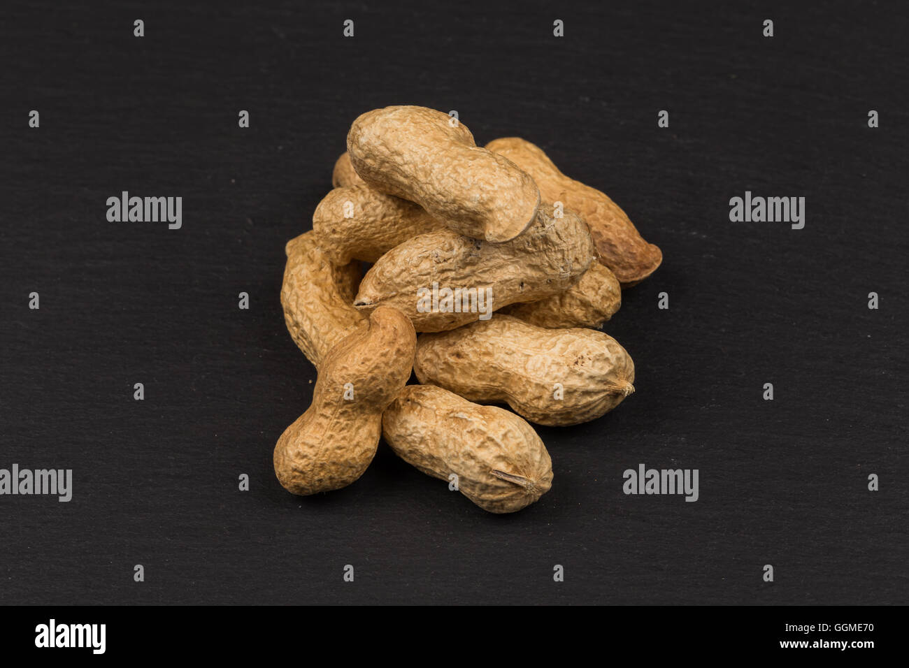 Raw peanuts shells over dark stone background Stock Photo - Alamy