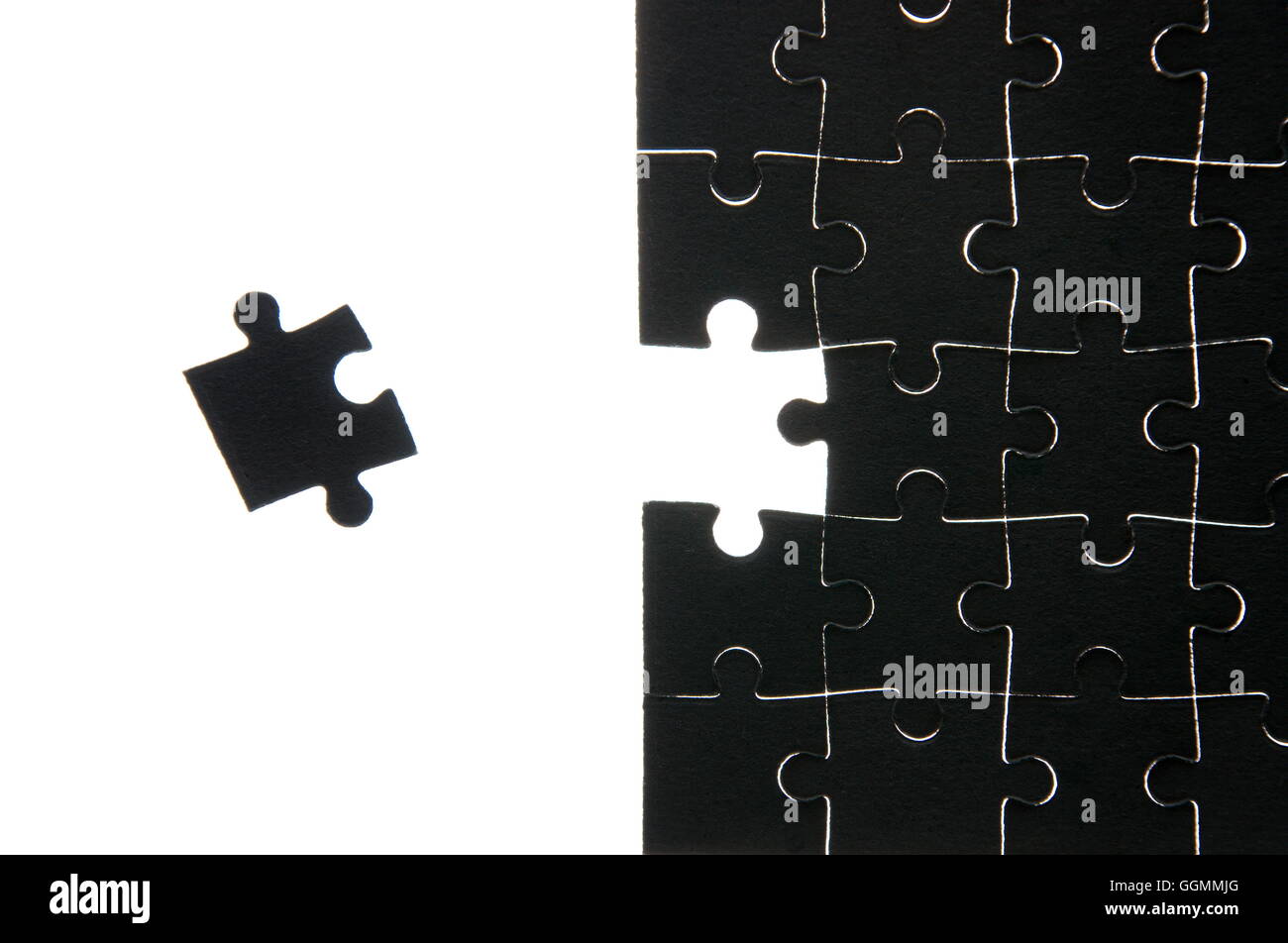 Assembled black puzzle without one element lying near him on a white ...