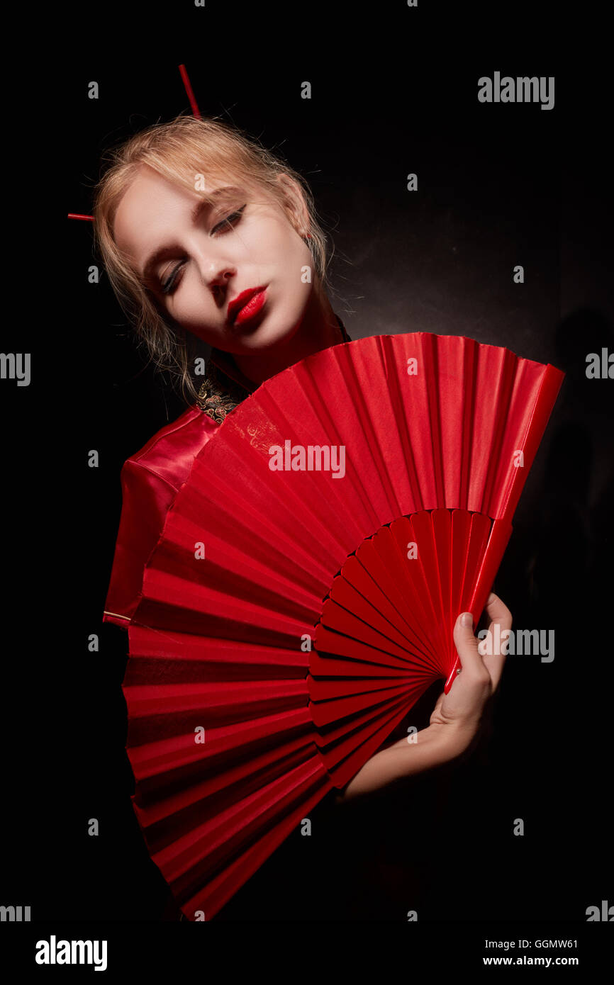 girl in geisha costume with red fan on black background Stock Photo - Alamy