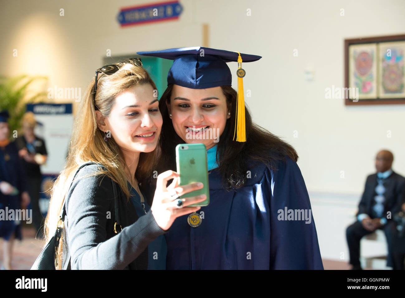 Happy graduate looks at cell phone picture after commencement ceremony ...