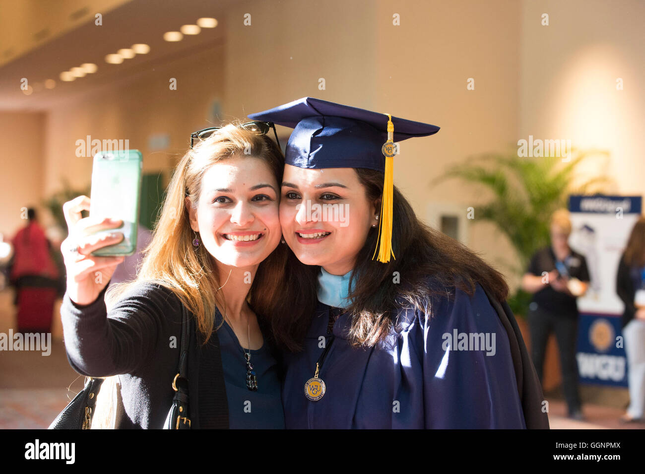 Happy graduate poses for cell phone picture after commencement ceremony ...
