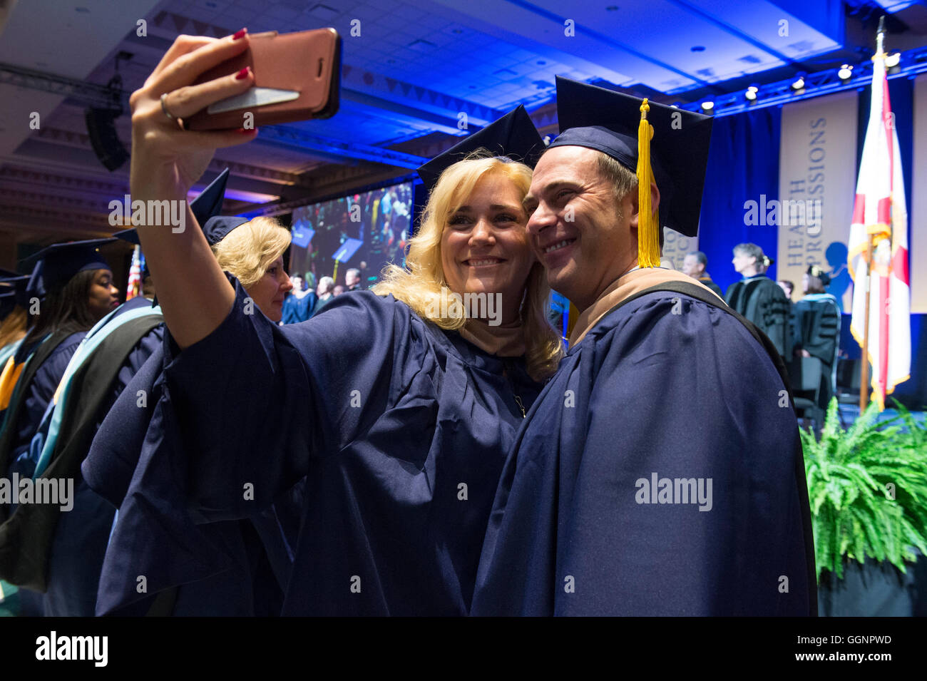 Happy graduates poses for cell phone picture during commencement ...