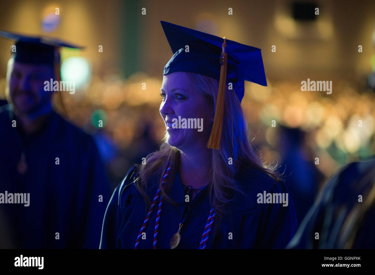 Graduation candidates in caps and gowns wait to receive diplomas at ...