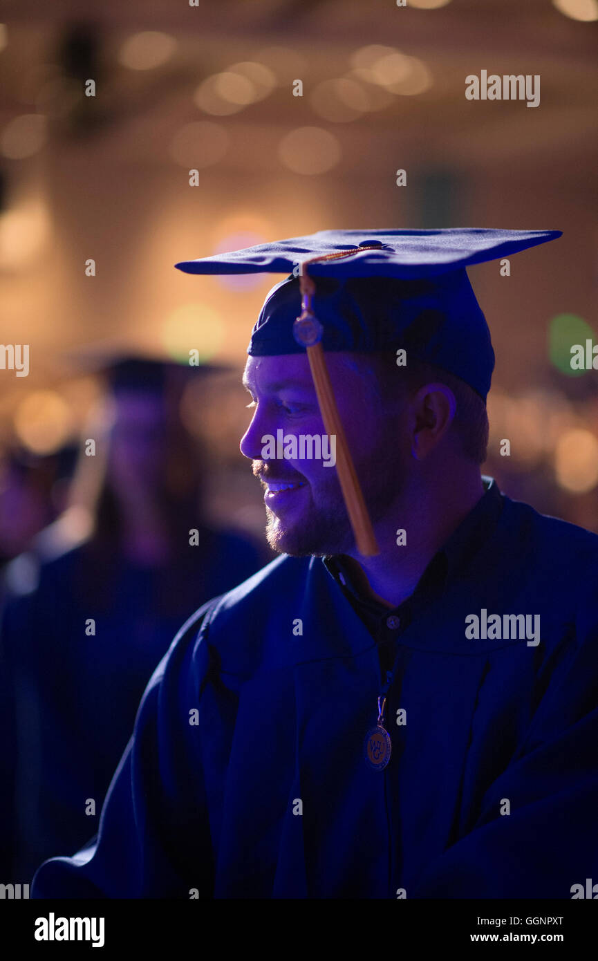 Graduation candidates in caps and gowns wait to receive diplomas at ...