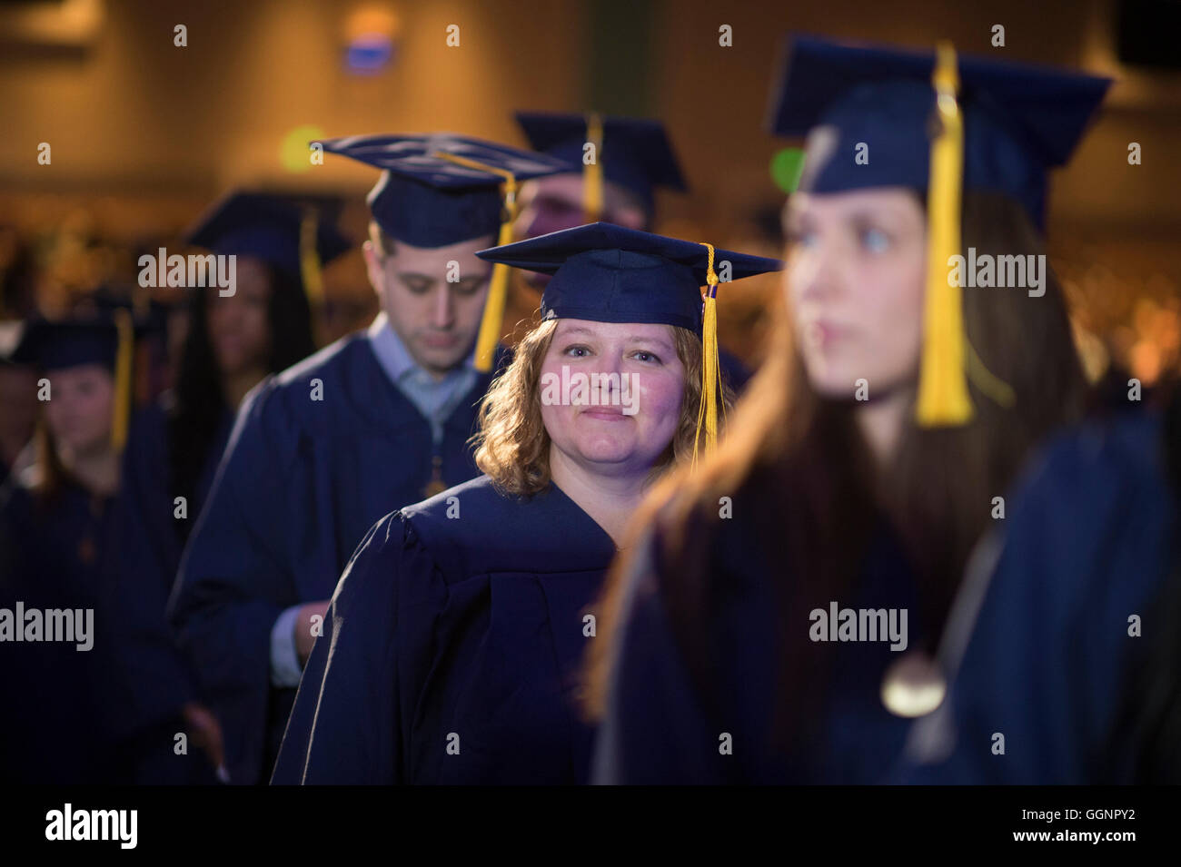 Graduation candidates in caps and gowns wait to receive diplomas at ...