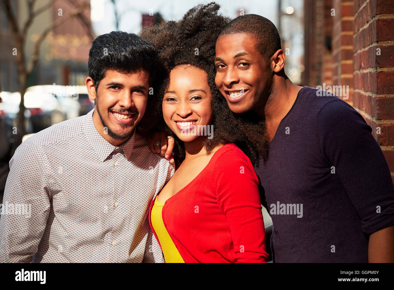 Smiling friends posing on city sidewalk Stock Photo - Alamy