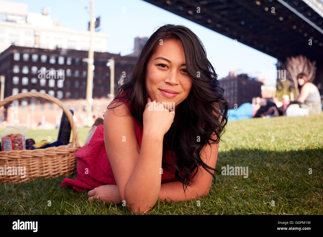 Pacific Islander woman laying on grass with picnic basket Stock Photo ...
