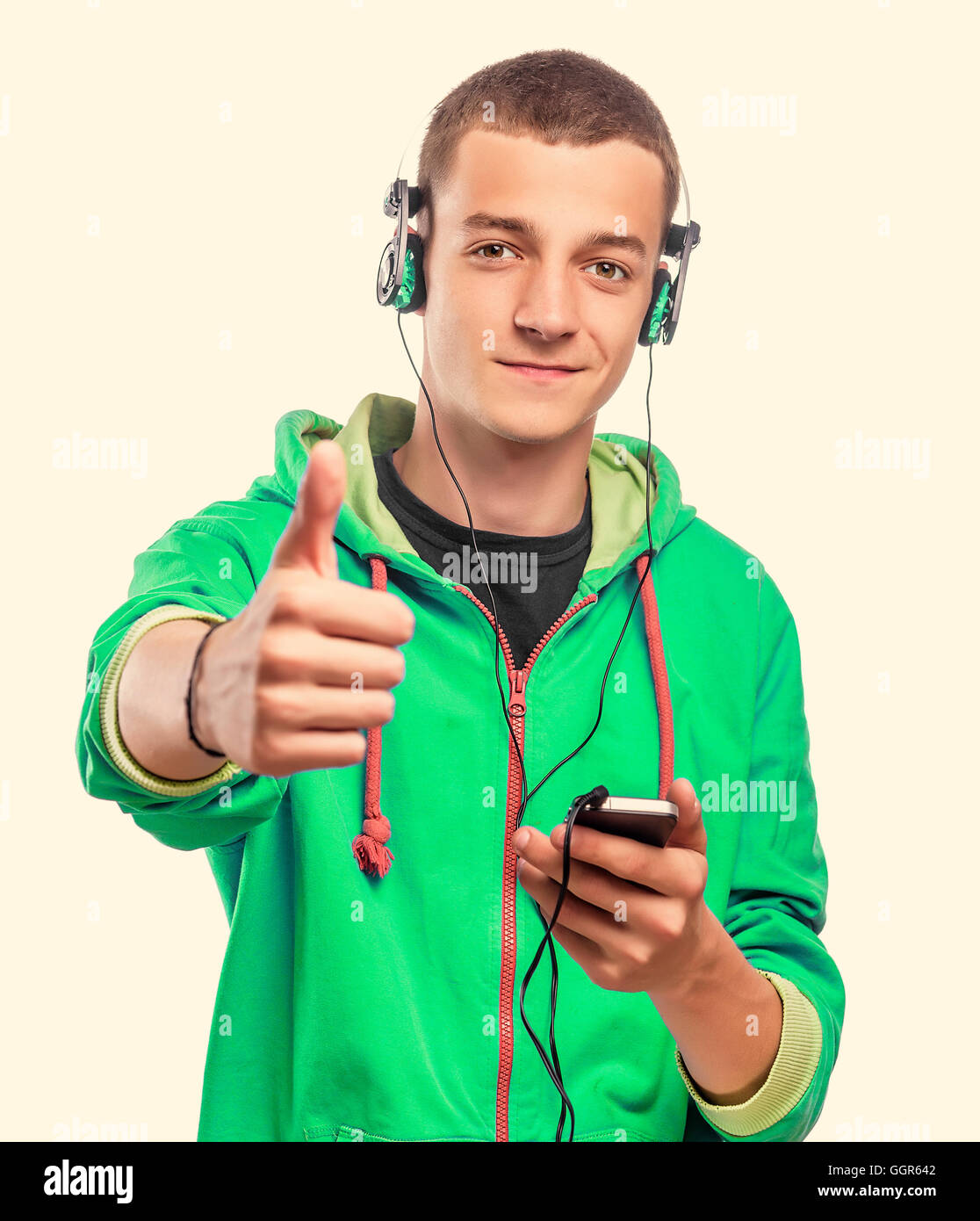 Handsome guy using phone with headphones showing thumbs up. Toned photo ...