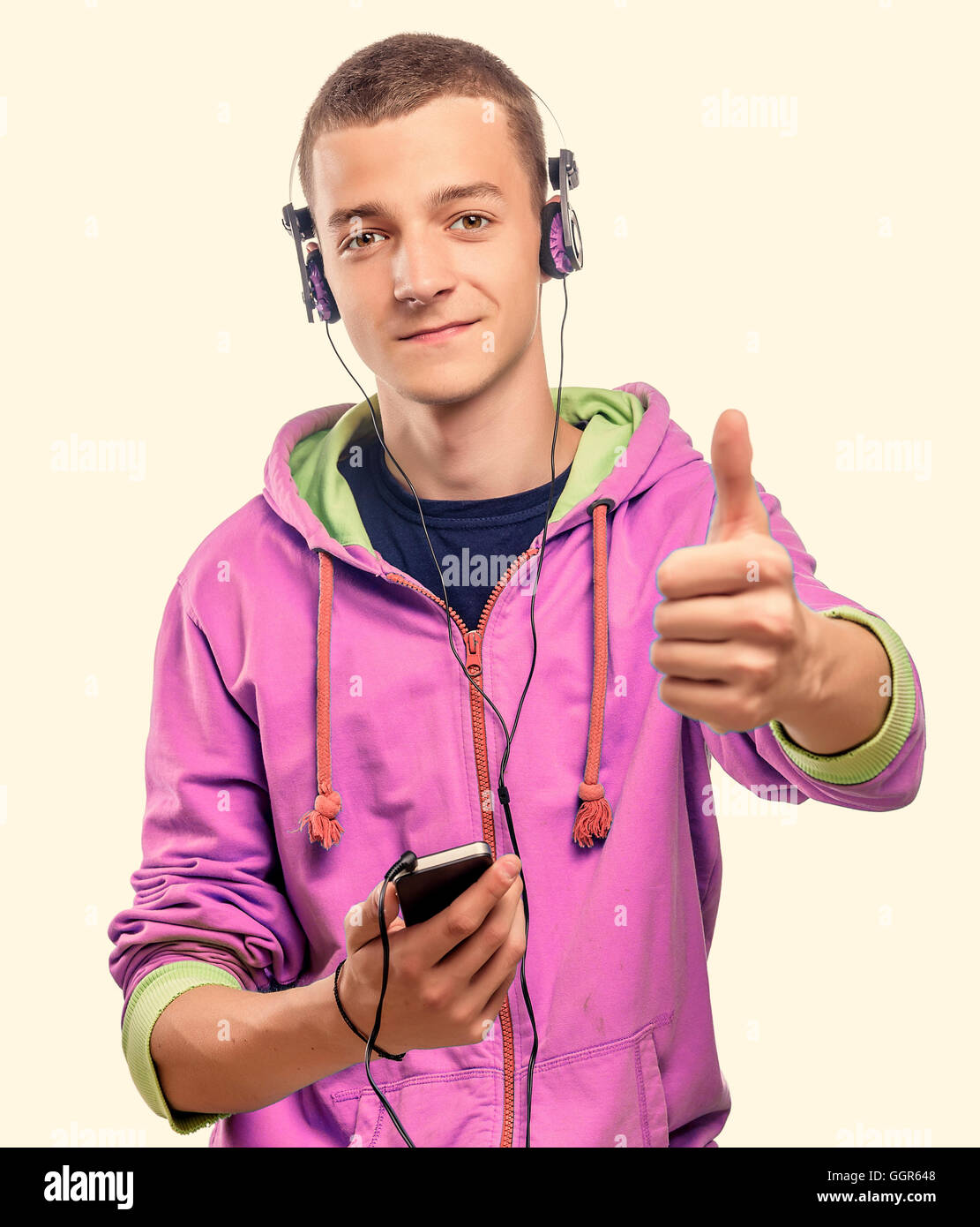 Handsome guy using phone with headphones showing thumbs up. Toned photo ...