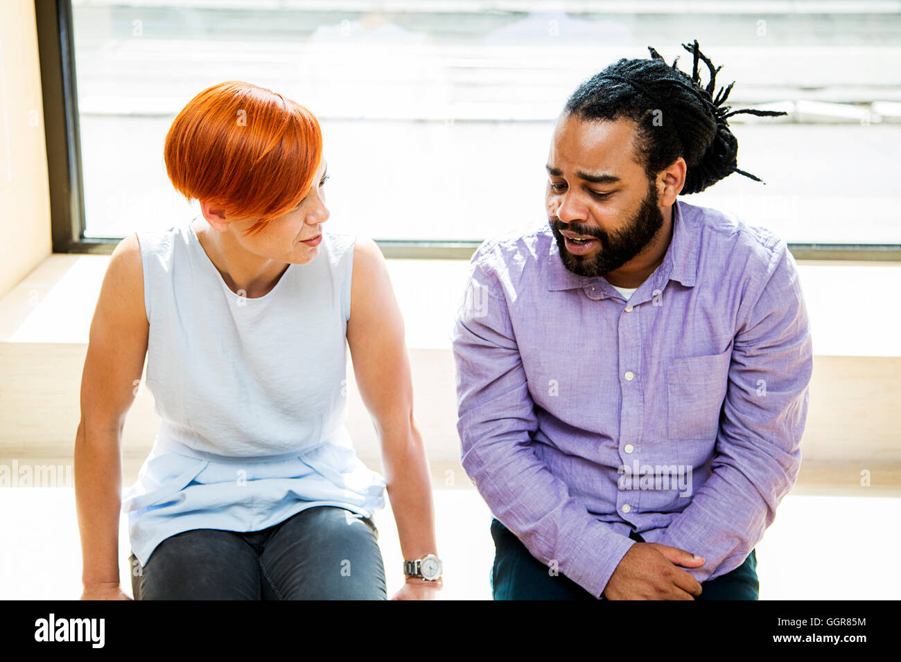 Redhaired young woman and black guy talking Stock Photo - Alamy