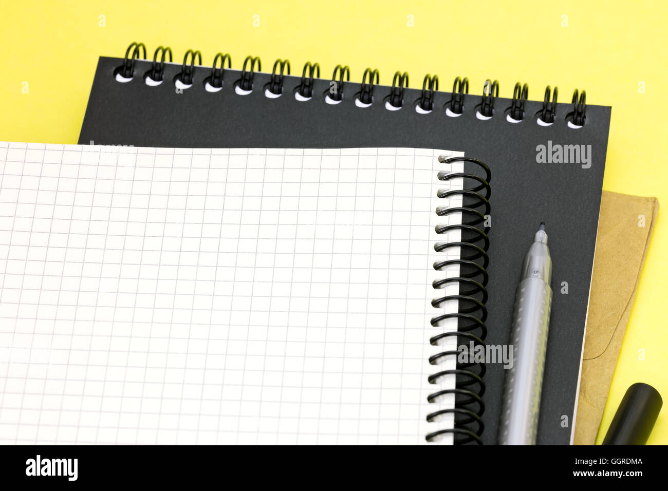 clean notepads, envelope, pen and marker on yellow writing desk ...