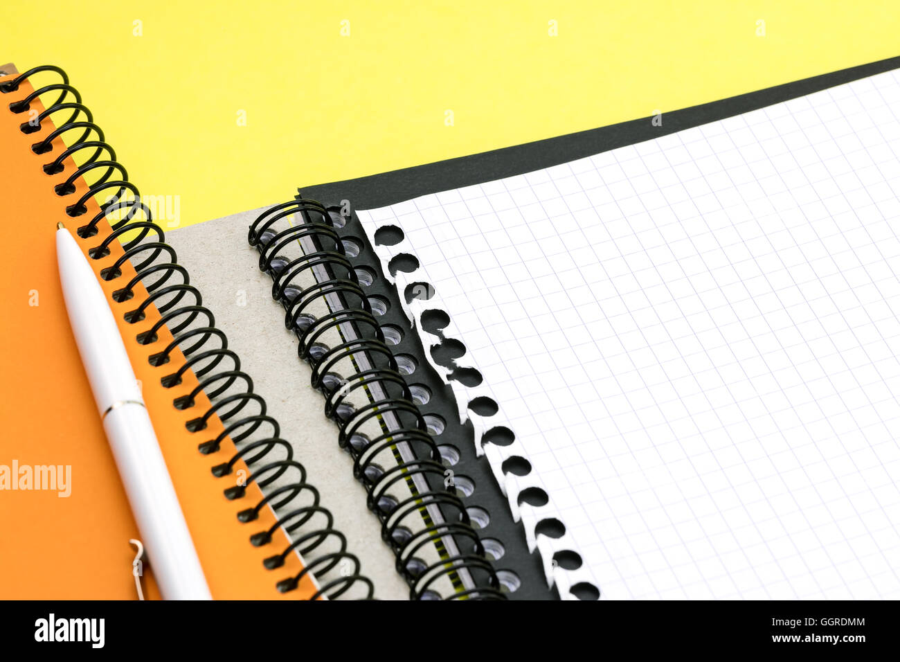 black and orange notepads, sheet of paper with pen on yellow writing ...
