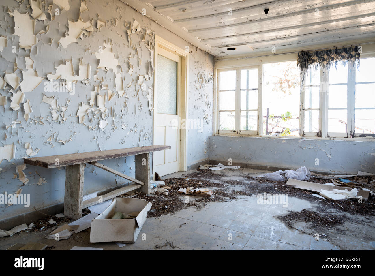 Interior of a damaged abandoned room with broken open windows and dirt ...