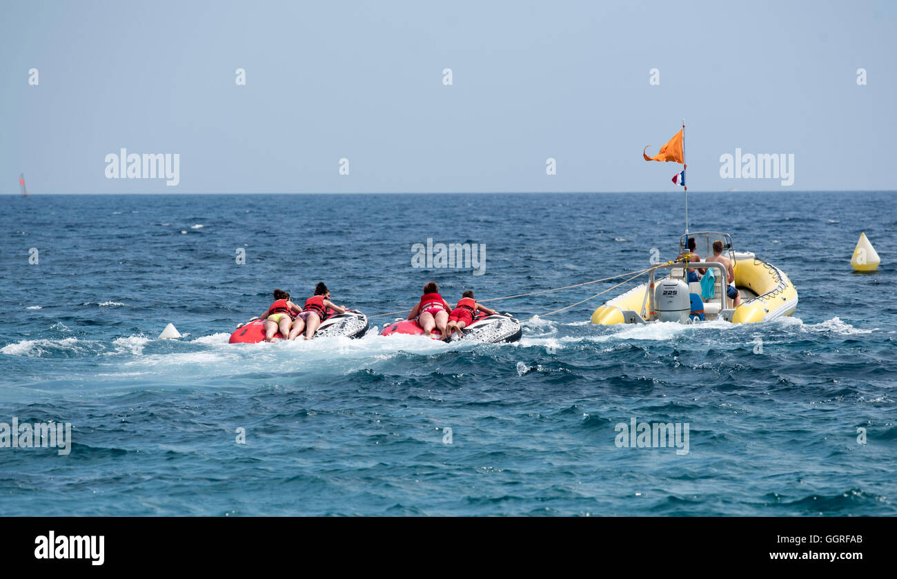 inflatable ride pulled along by speedboat beach fun Stock Photo - Alamy