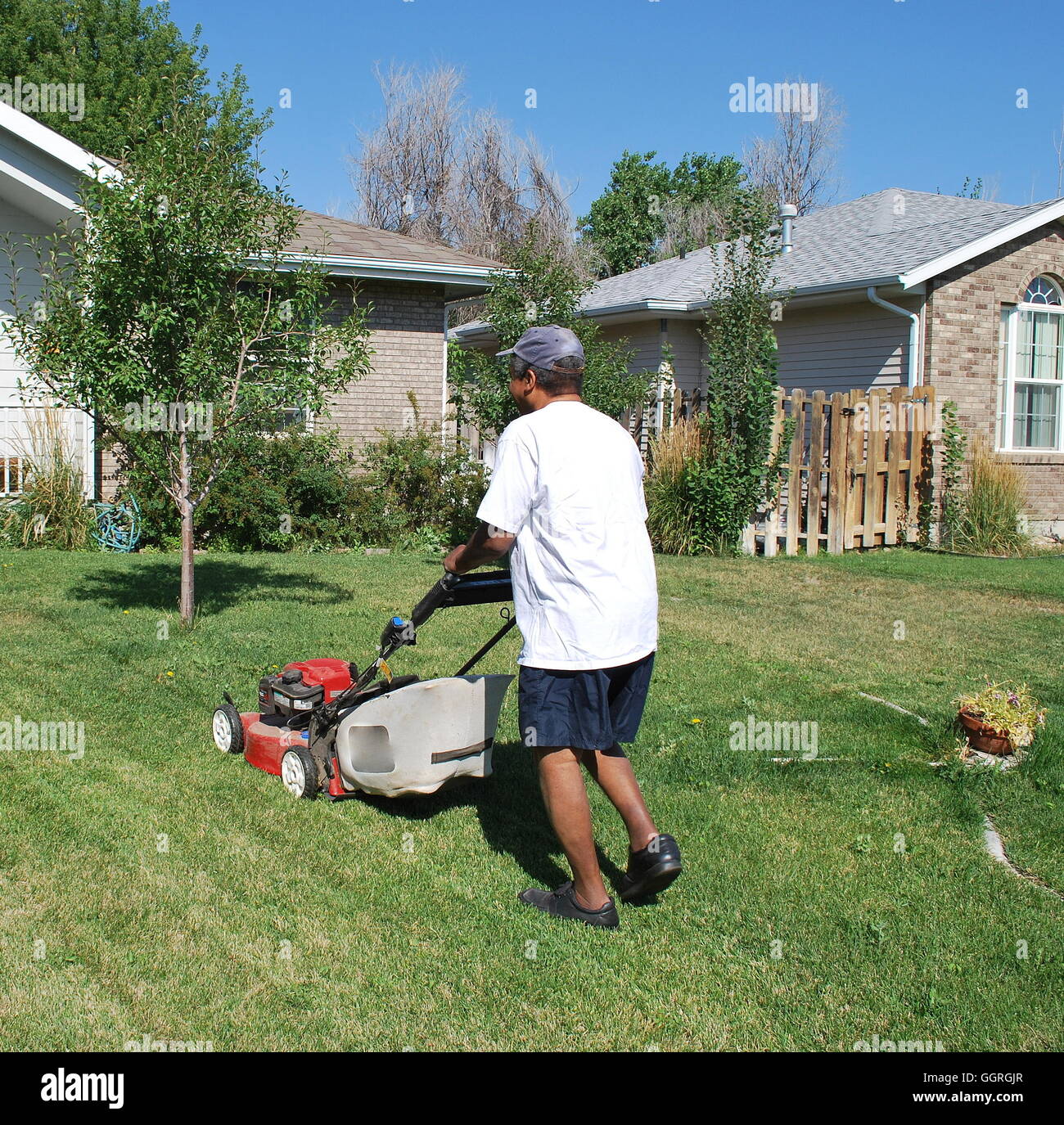 Man mowing the lawn outside Stock Photo - Alamy