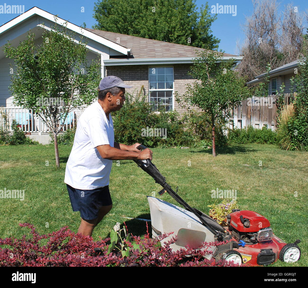 Man mowing the lawn outside Stock Photo - Alamy