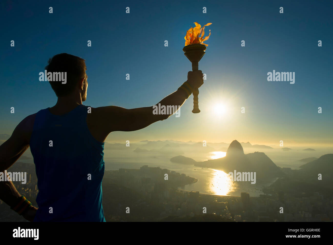 Torchbearer athlete holding sport torch standing in silhouette against ...