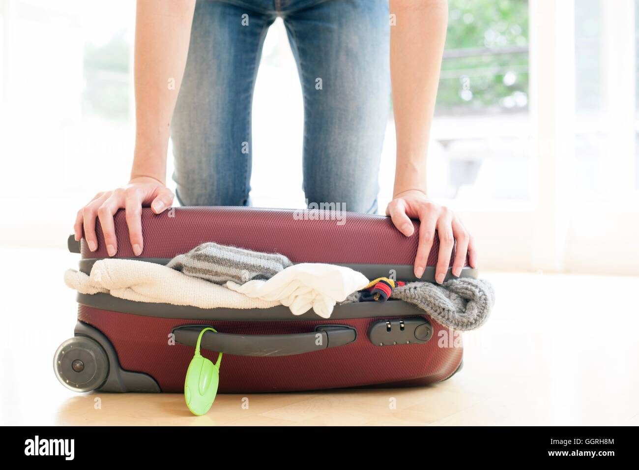 Woman packing, pushing down on full suitcase Stock Photo - Alamy