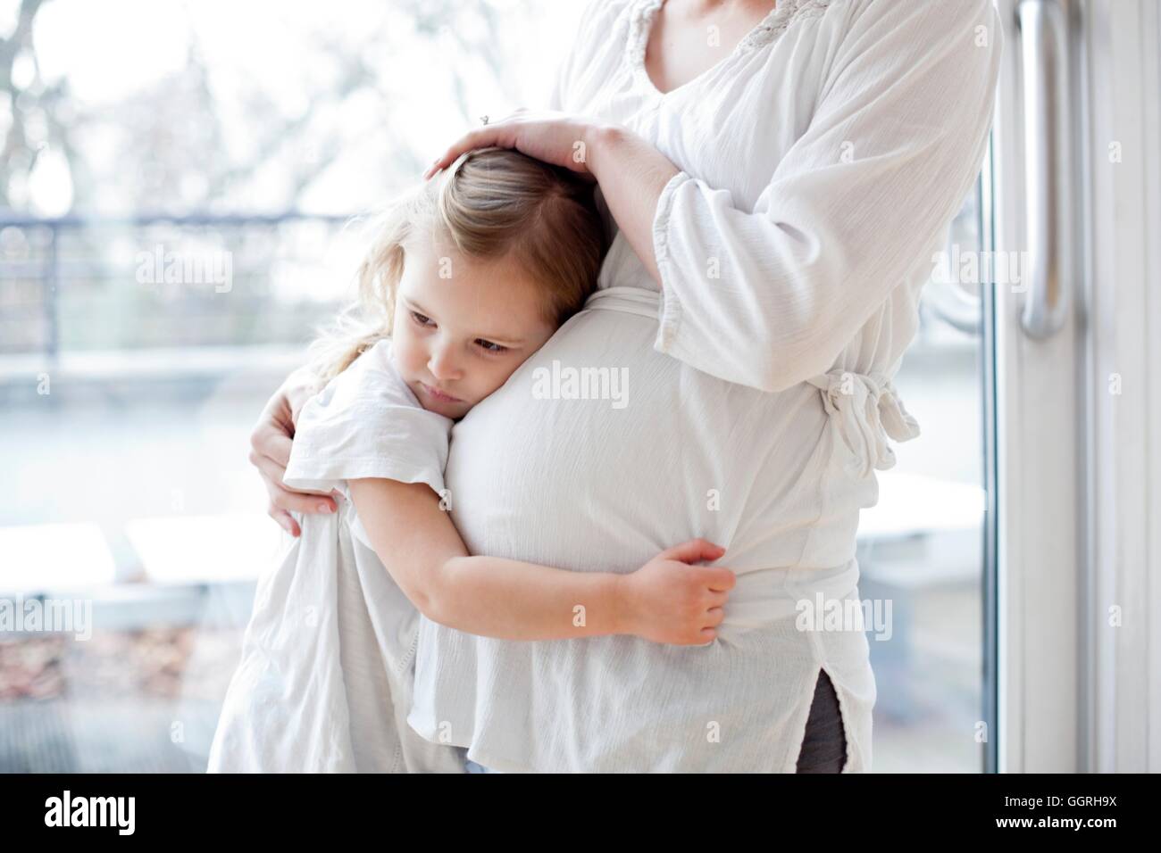 Pregnant mother with arms around daughter Stock Photo - Alamy