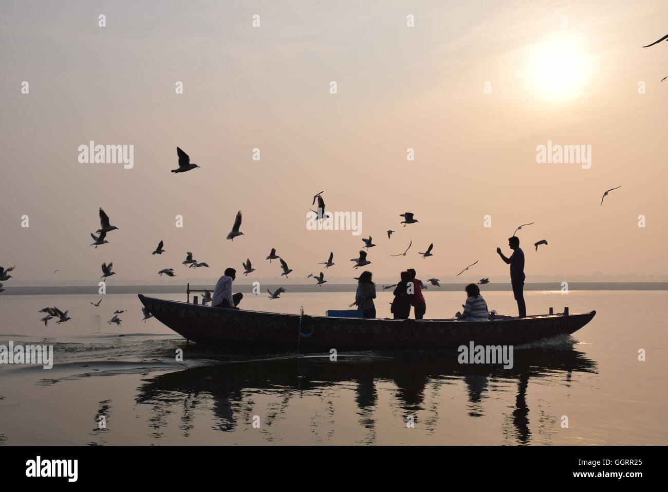 Boat with tourists and birds floating of river Ganga after sunrise ...