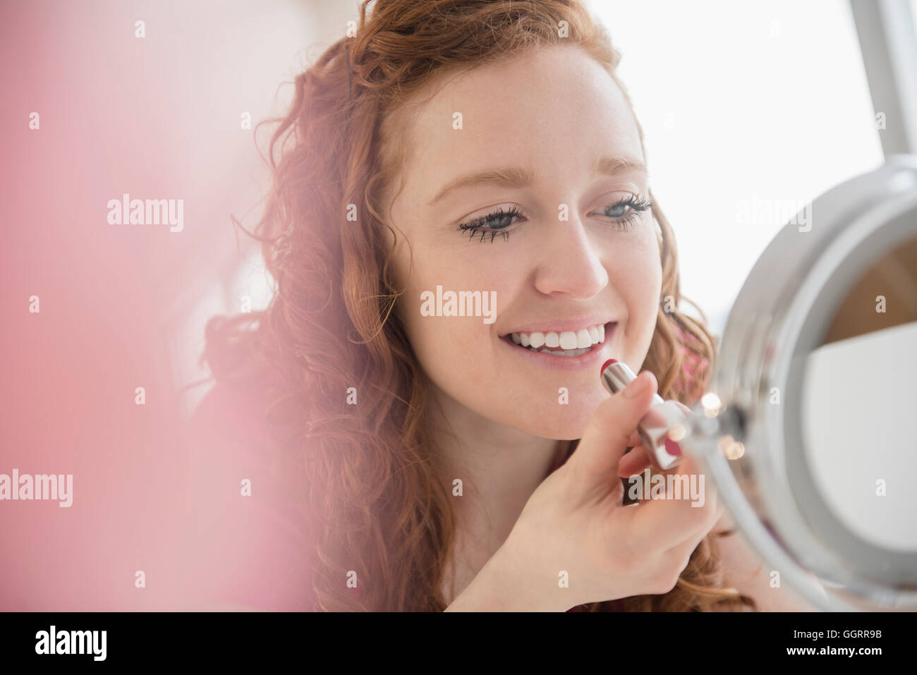 Woman applying red lipstick in mirror hi-res stock photography and ...