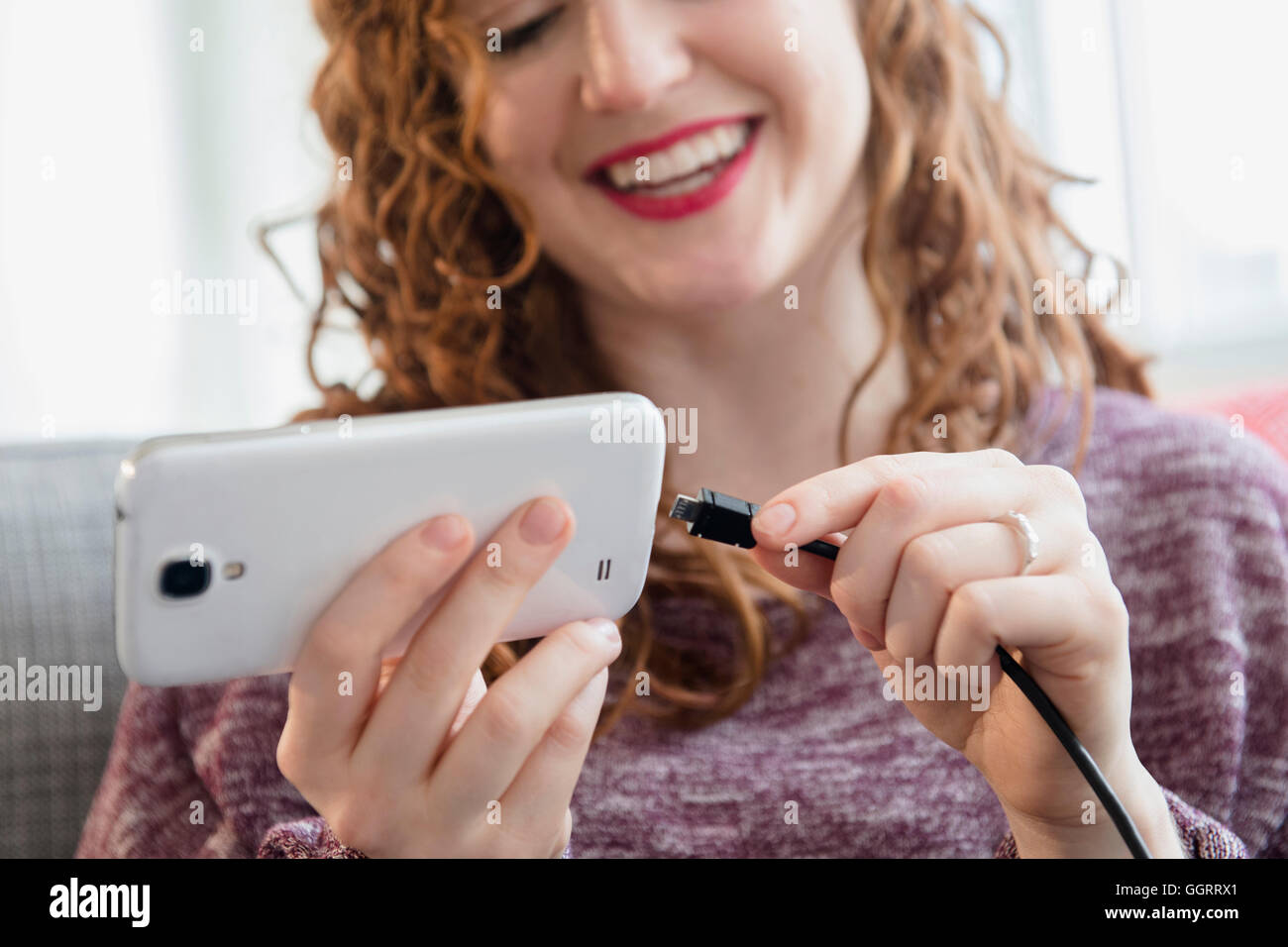 Caucasian woman connecting cord to cell phone Stock Photo - Alamy