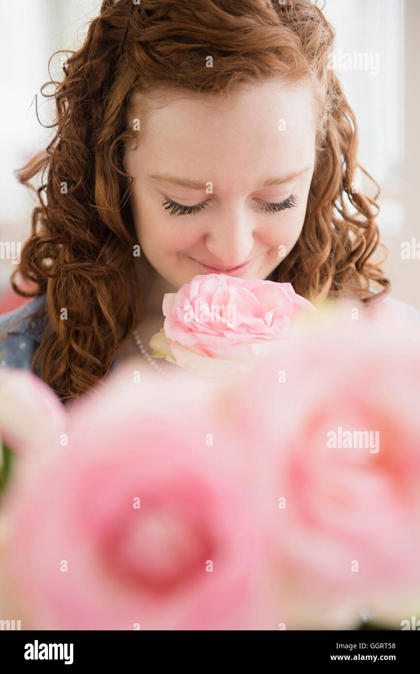 Caucasian woman smelling pink rose Stock Photo - Alamy