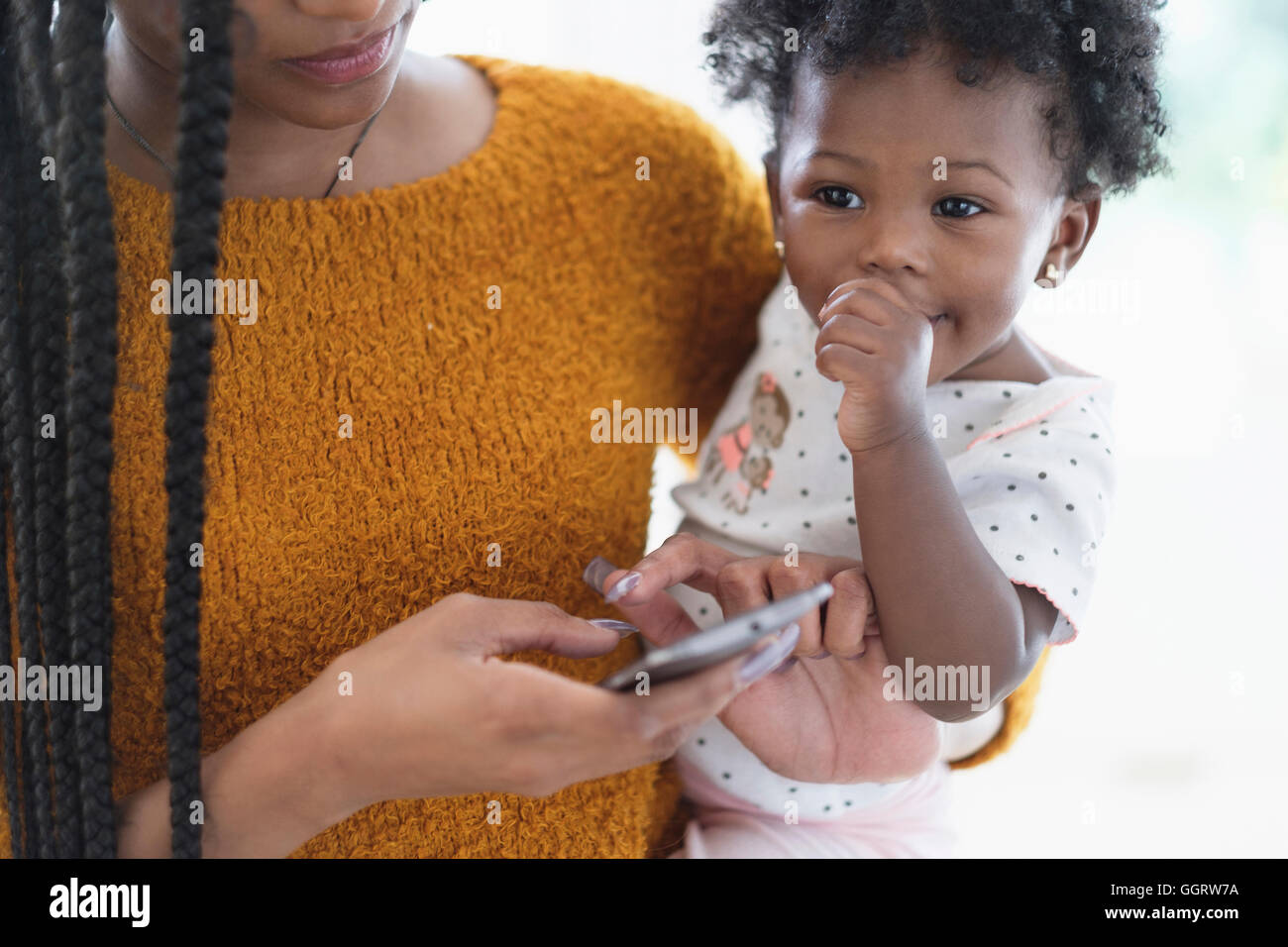 Black woman holding baby daughter using cell phone Stock Photo - Alamy