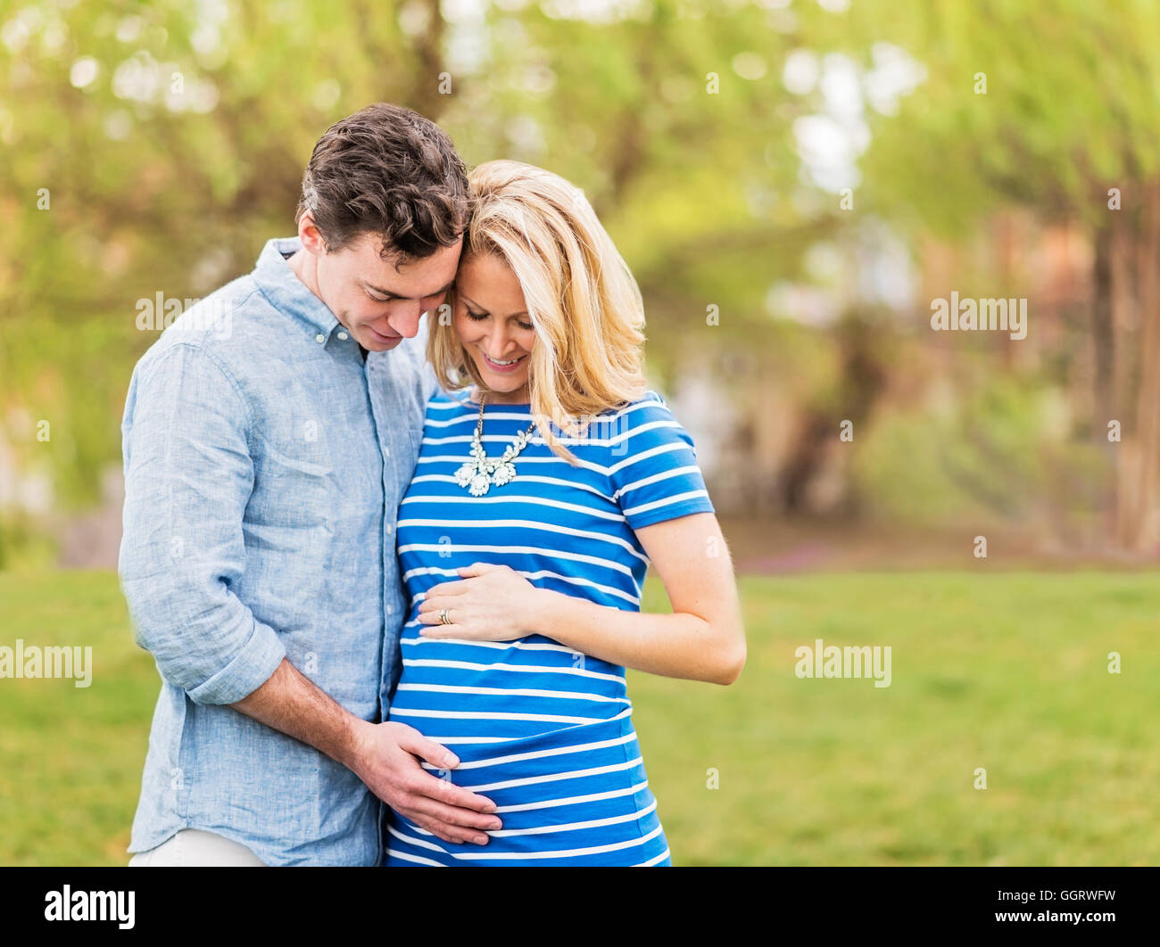 Smiling Caucasian man and expectant mother looking at belly Stock Photo ...