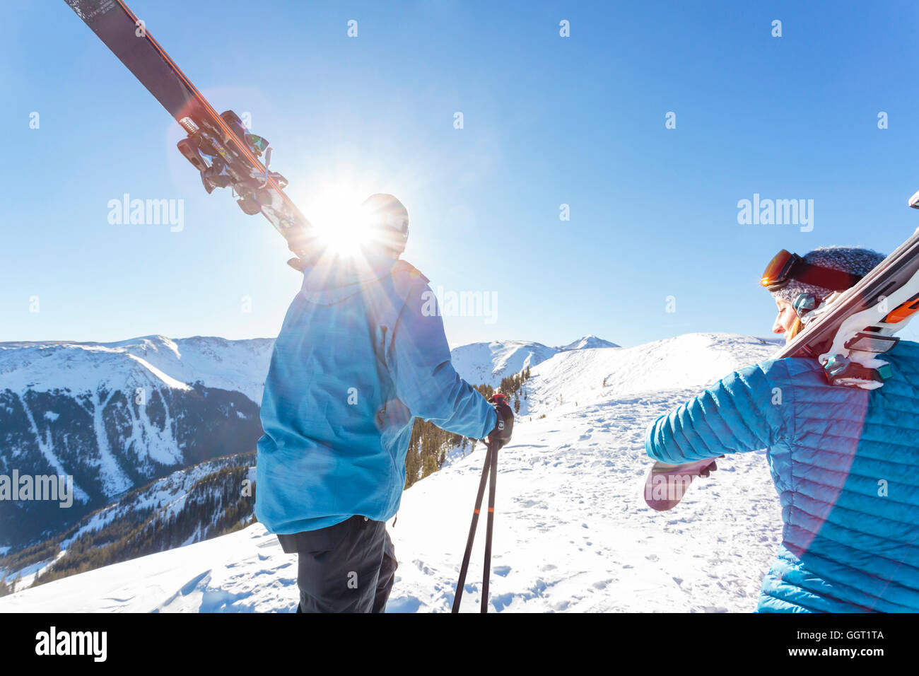 Couple carrying skis on snowy mountain Stock Photo - Alamy