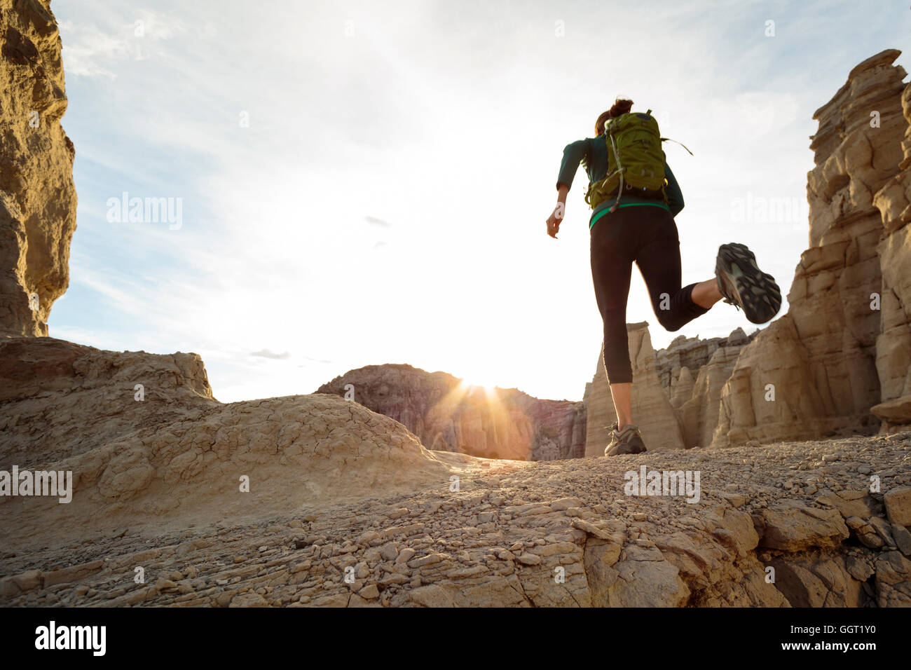 Woman running in canyon wearing backpack Stock Photo - Alamy