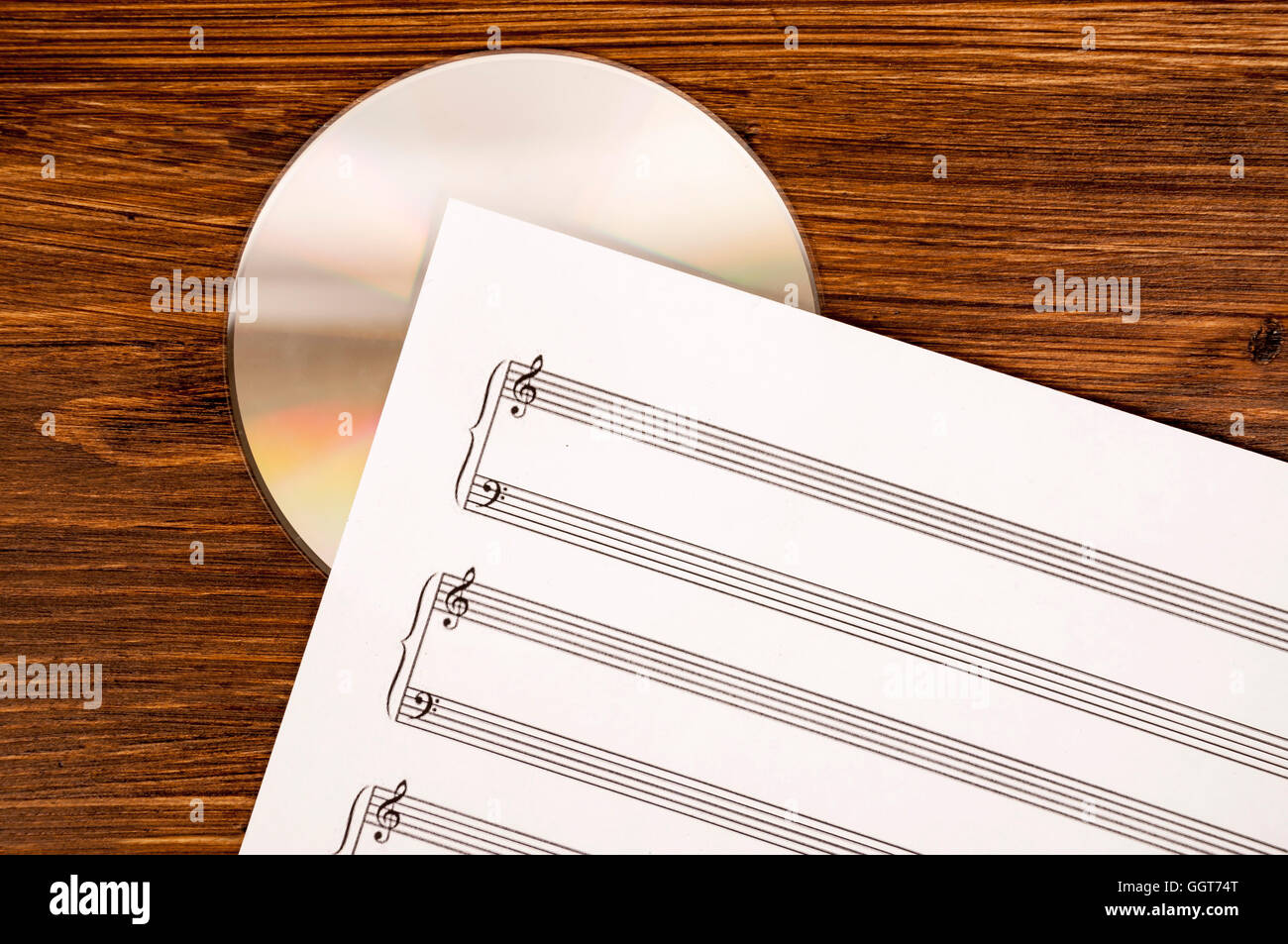 Music sheet and CD drive on wooden background. Old and new technology ...