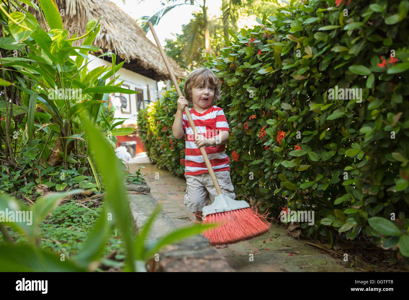Caucasian boy playing with broom on path near house Stock Photo - Alamy