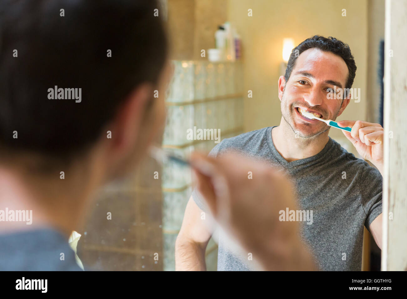 Hispanic man brushing teeth in mirror Stock Photo - Alamy